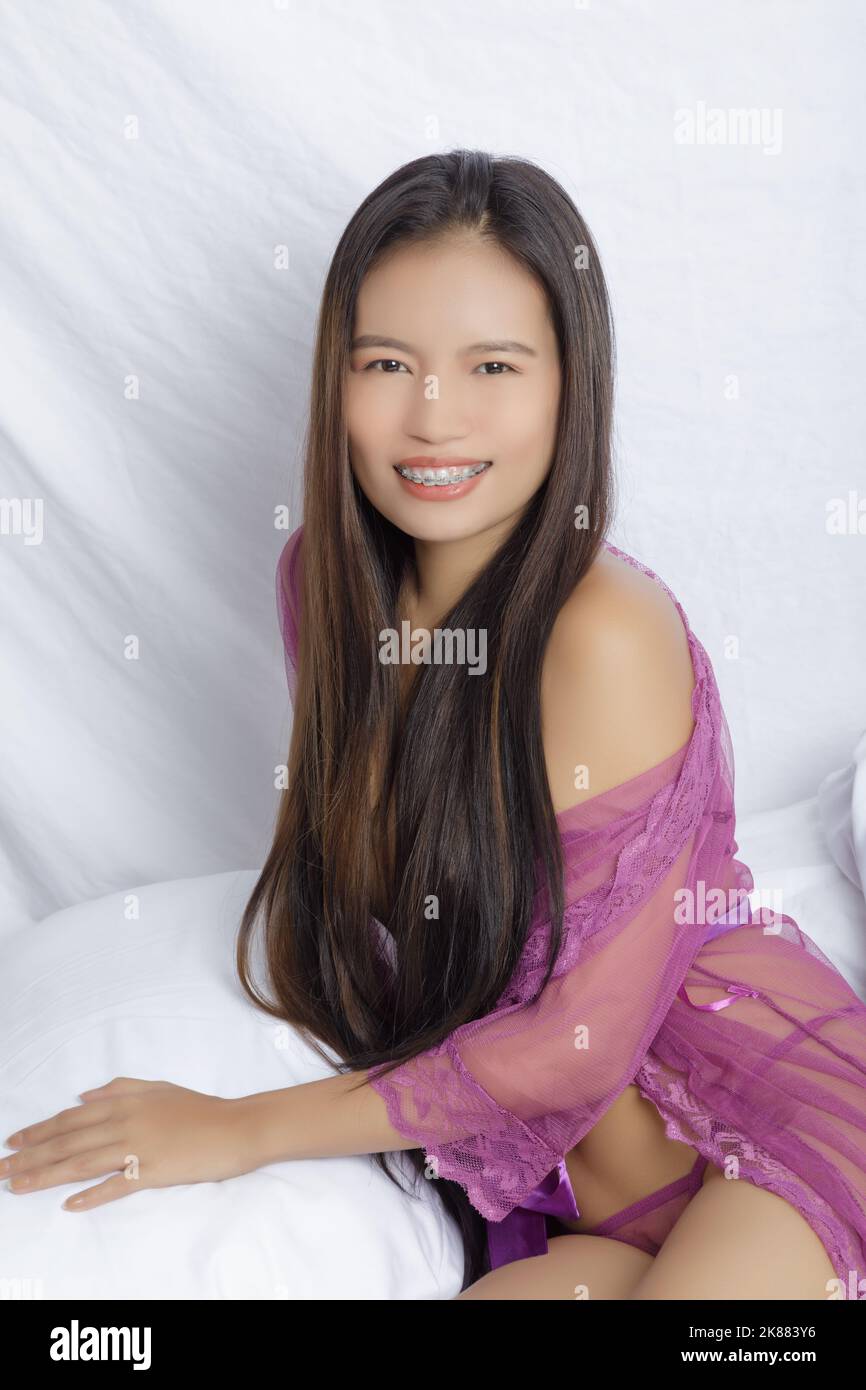 Beautiful Philippine woman posing in sexy Purple Silk Lngerie isolated on a white background ...