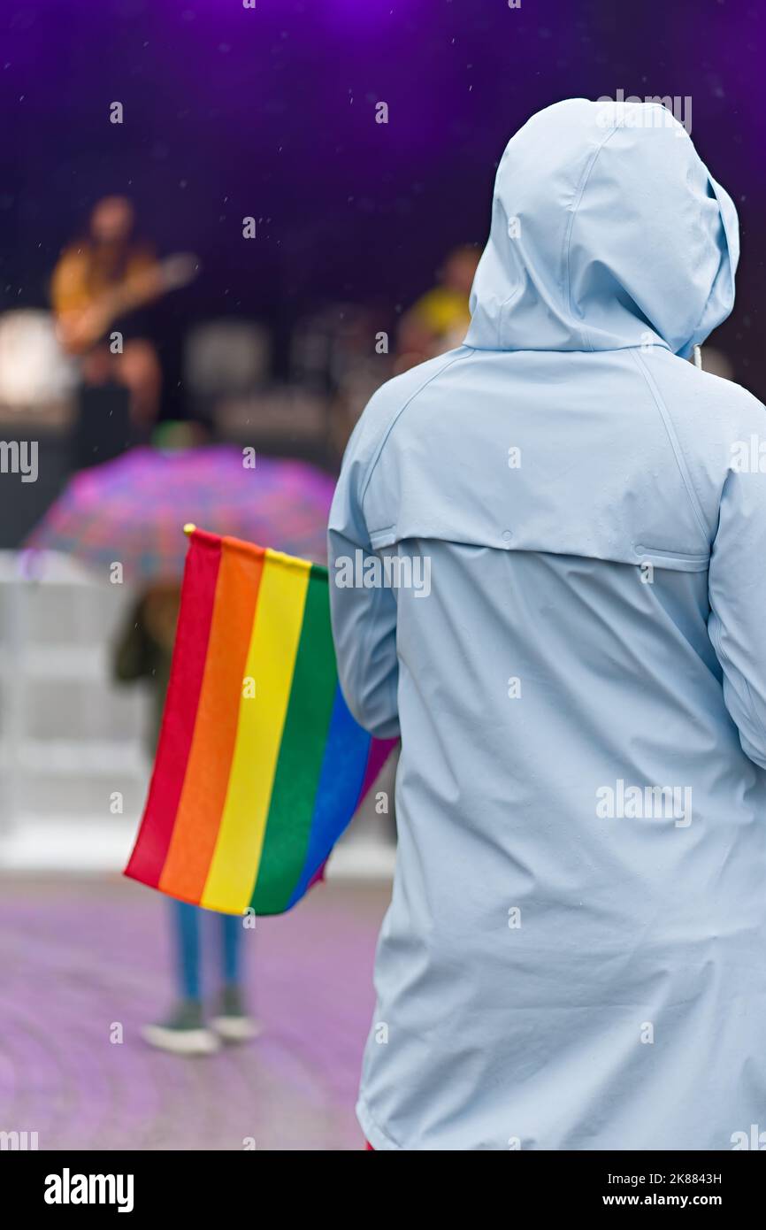 A person facing backwards in a blue jacket with the pride flag at the ...