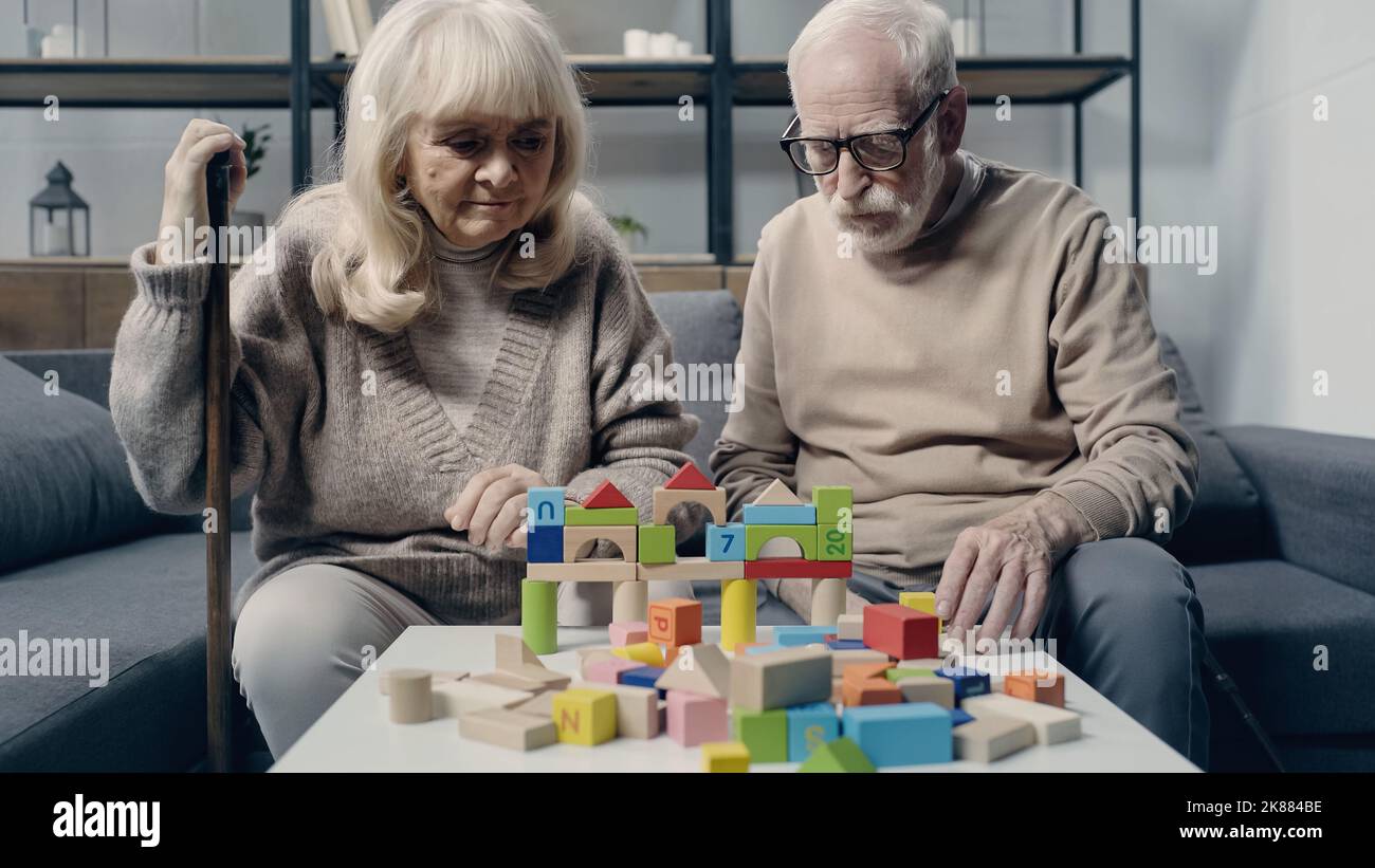 Senior couple with dementia playing with colorful building blocks on ...