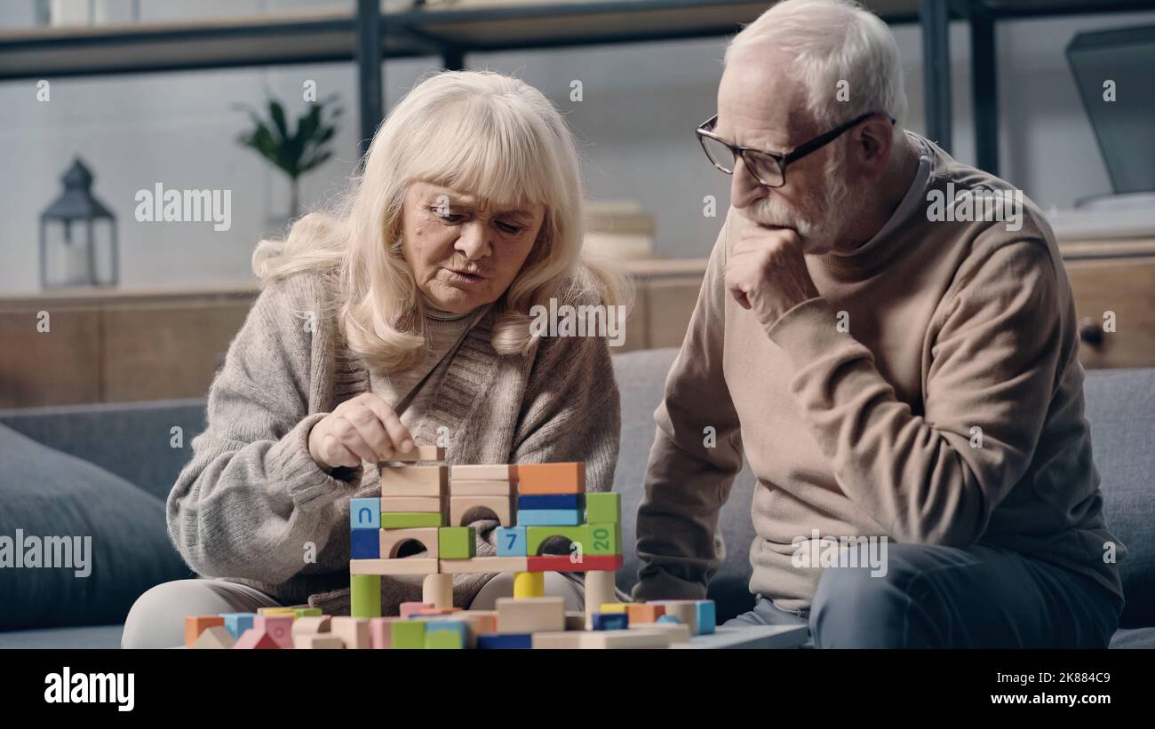 retired woman with dementia playing with colorful building blocks near ...