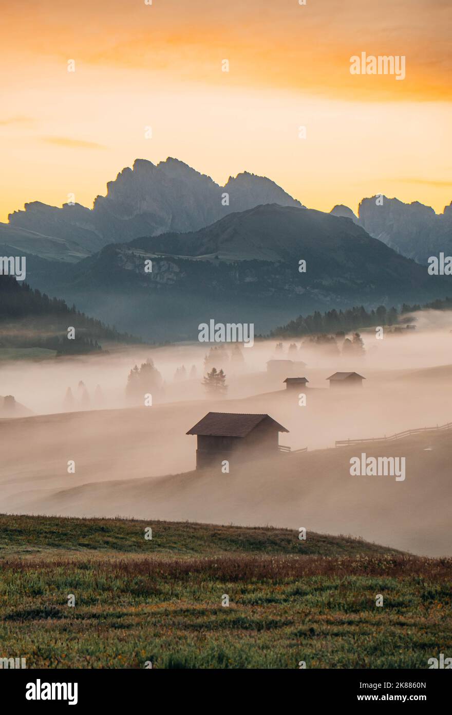 A vertical of a small house in a fog in Seiser Alm meadow, Italy with ...