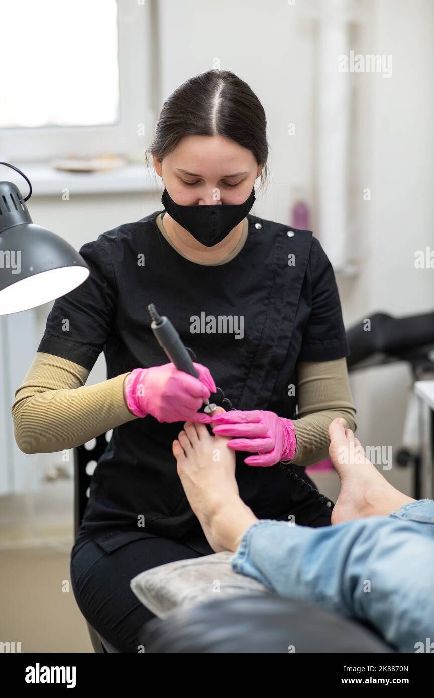 The pedicure master processes the client's foot using an apparatus with ...