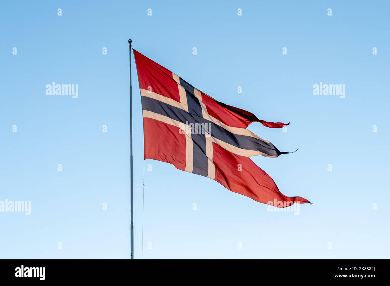 A waving Norwegian swallowtail flag with blue sky in the background ...