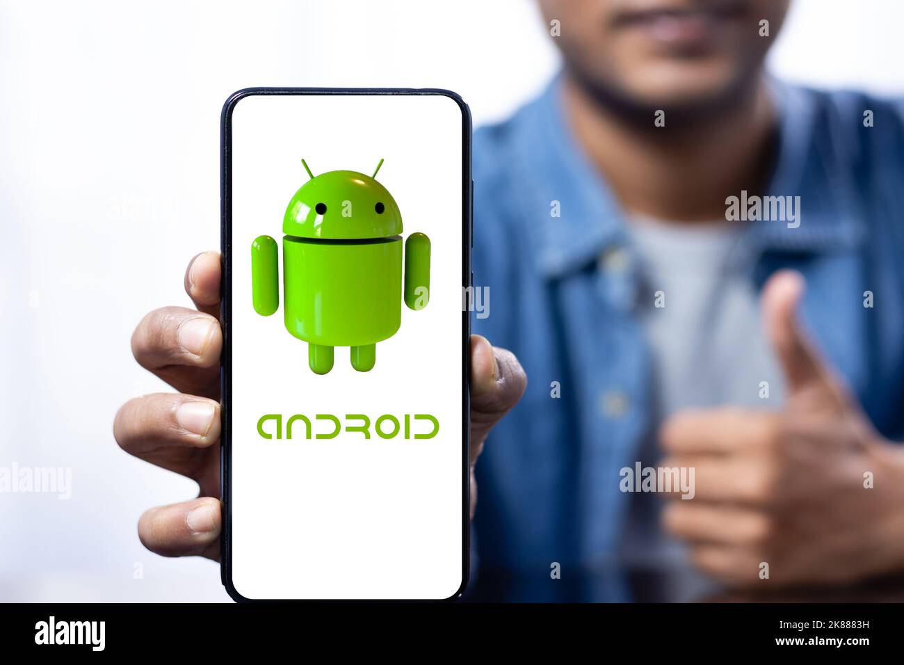 Close up of a smart phone screen with android logo held in hand by an ...