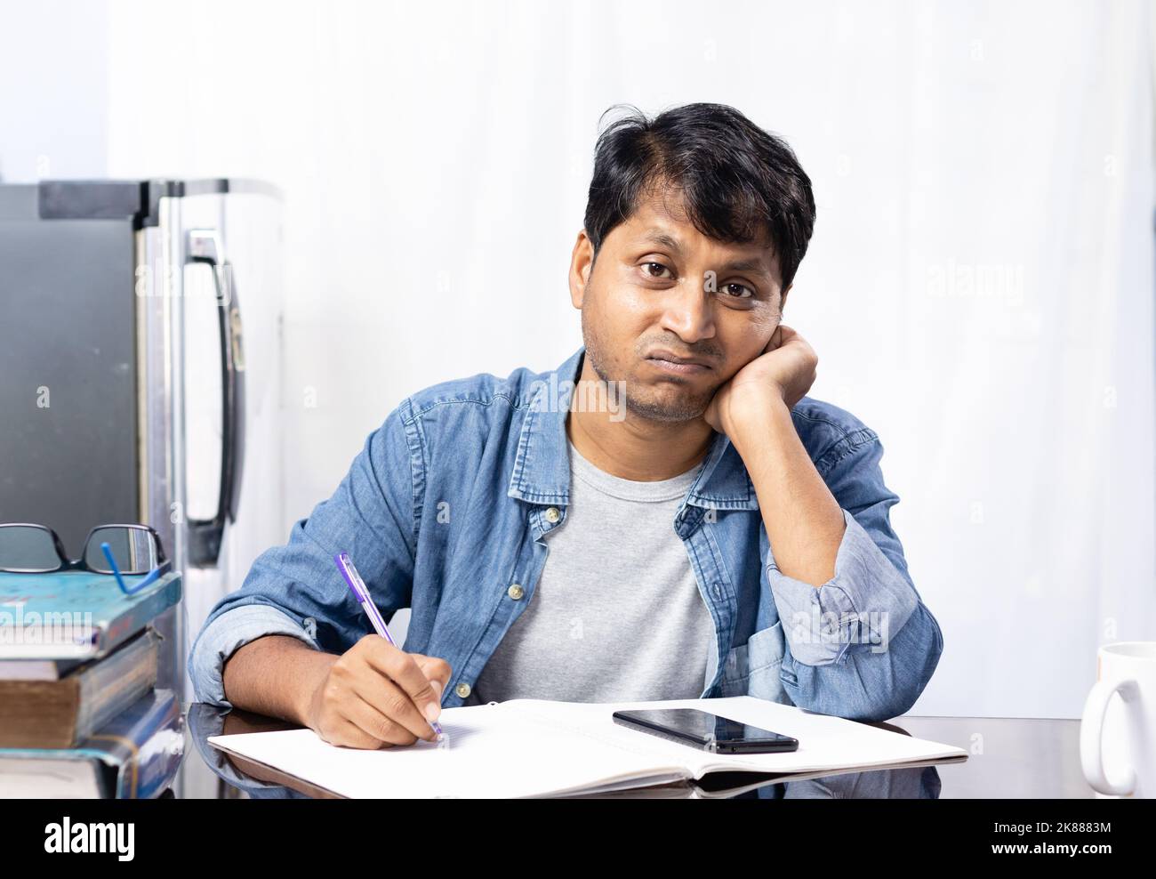 An Indian young male looking worried and thinking while studying at ...