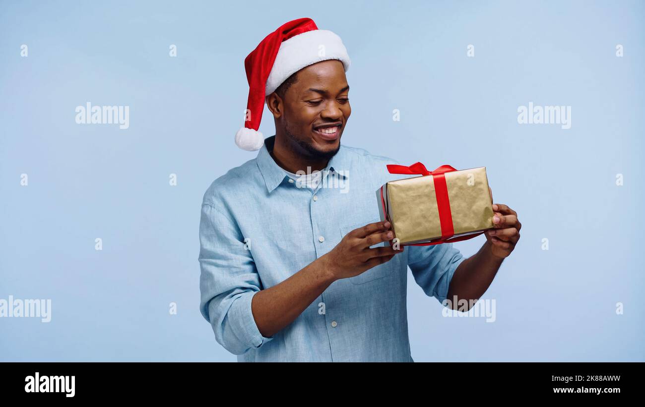 happy african american man in santa hat holding christmas gift box ...