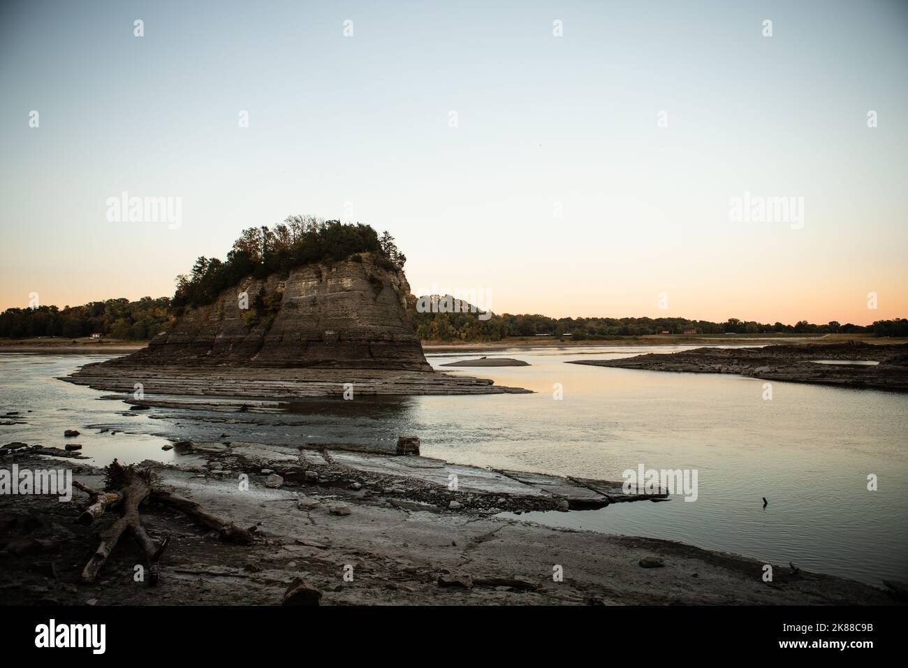 Sunset landscape of towering rock island on river Stock Photo - Alamy