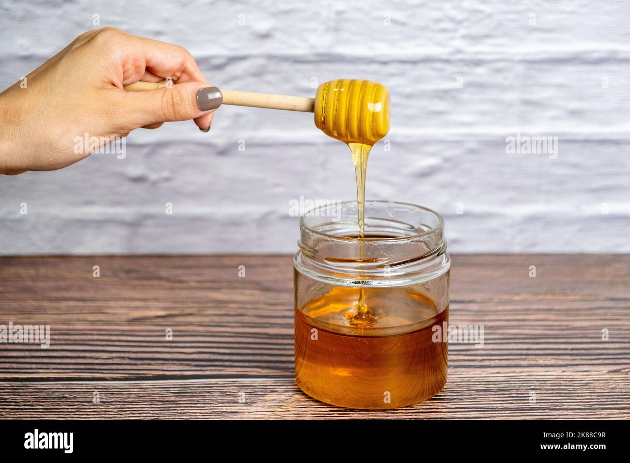 Honey drizzling. Pot of honey and wooden stick isolated white br Stock ...