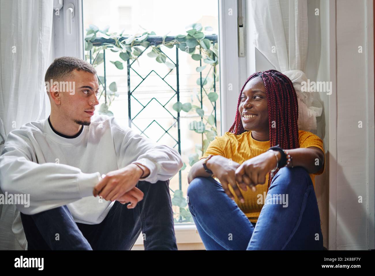 Multiracial couple talking sitting on the floor at home Stock Photo - Alamy