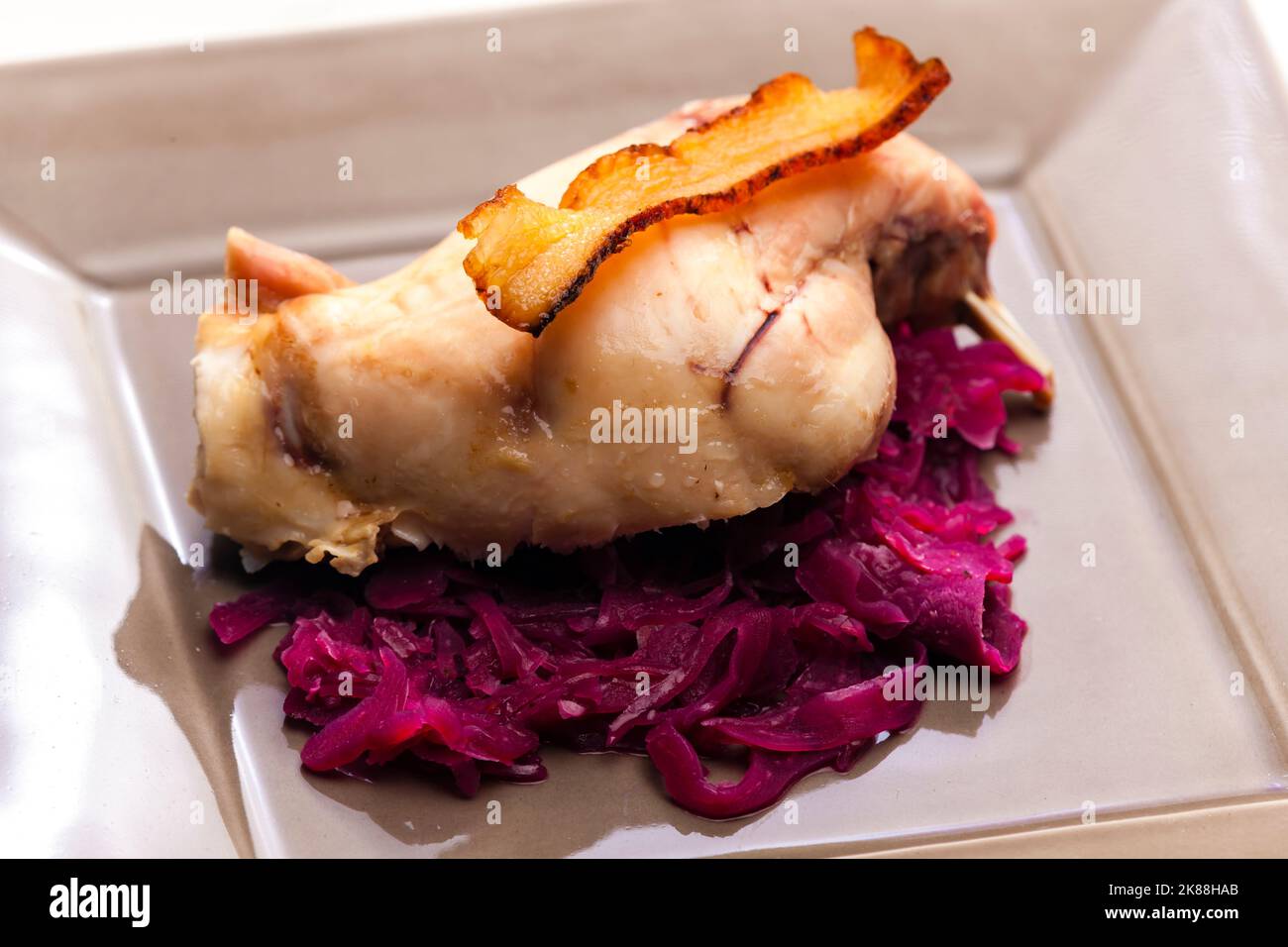 rabbit leg baked with bacon and served with red cabbage Stock Photo - Alamy