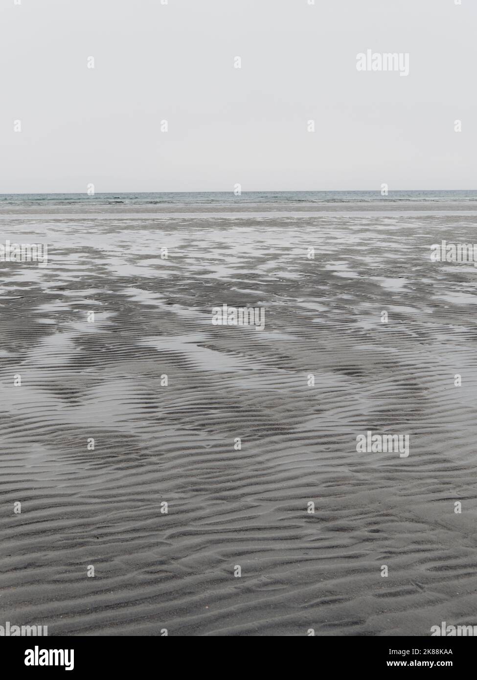 Wet wavy sand on the seashore at low tide on a cloudy day. Gloomy ...