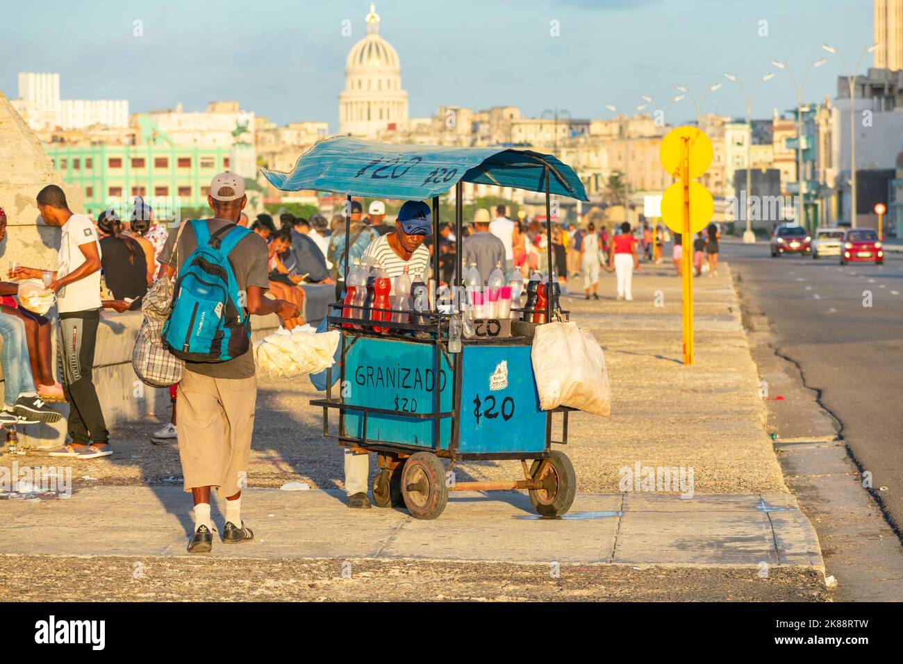 A group of people buying flavored ice in a small business cart in El ...