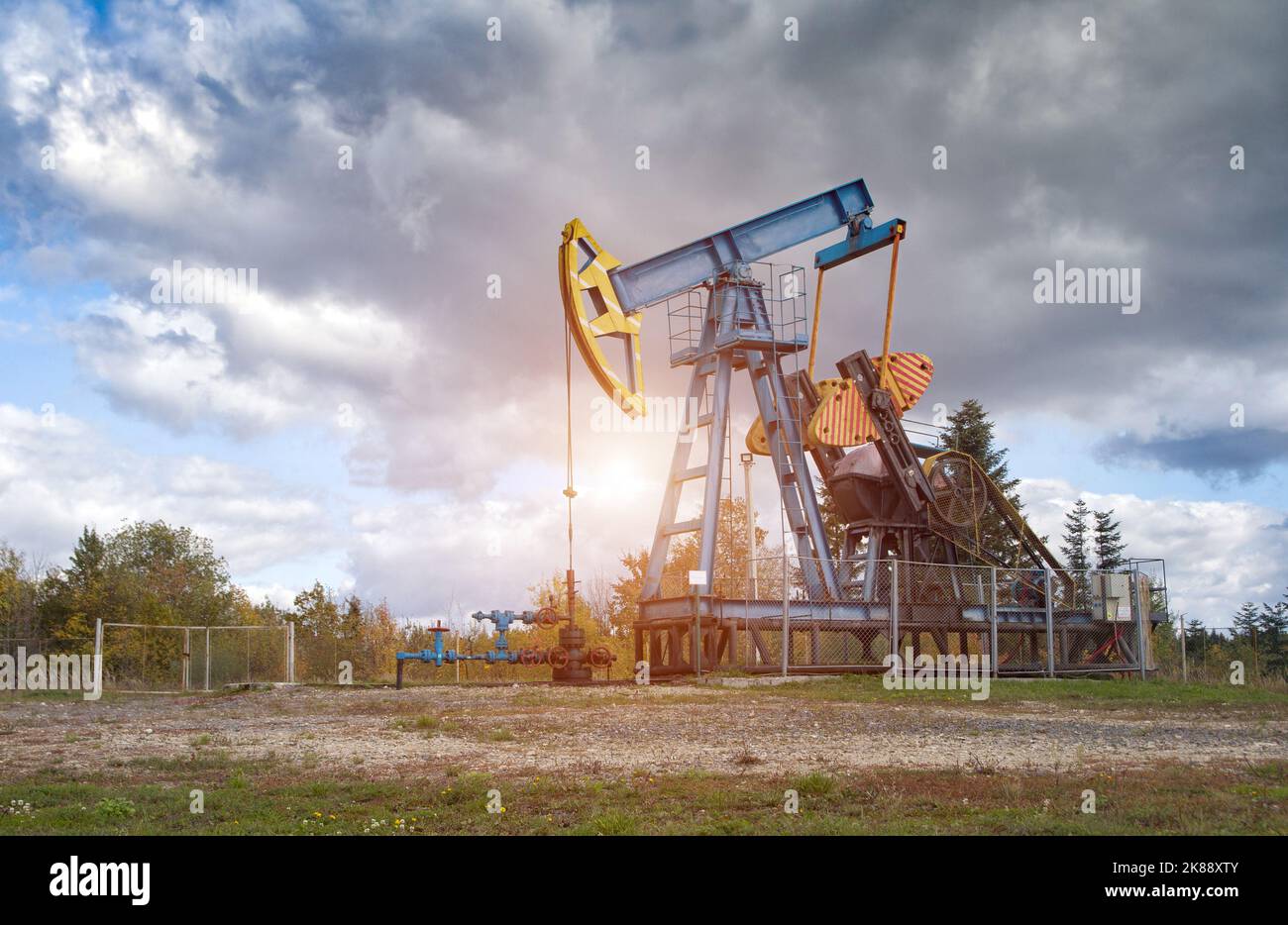 Oil rig pump rocking chair against the background of the autumn forest ...