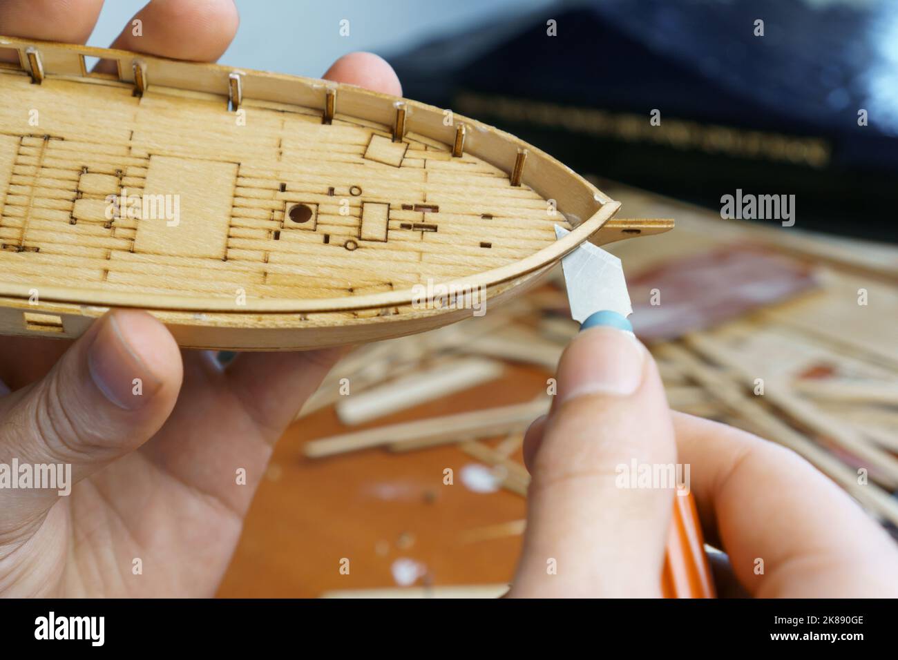 Hands of man cutting out details for ship model with clerical knife ...