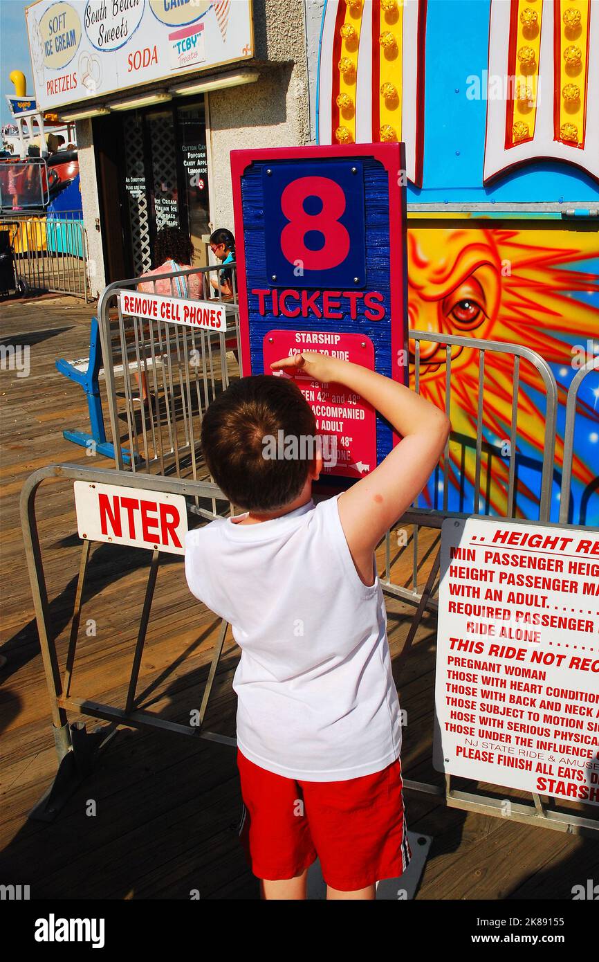 A young boy checks his height to see if he is tall enough to ride a ...