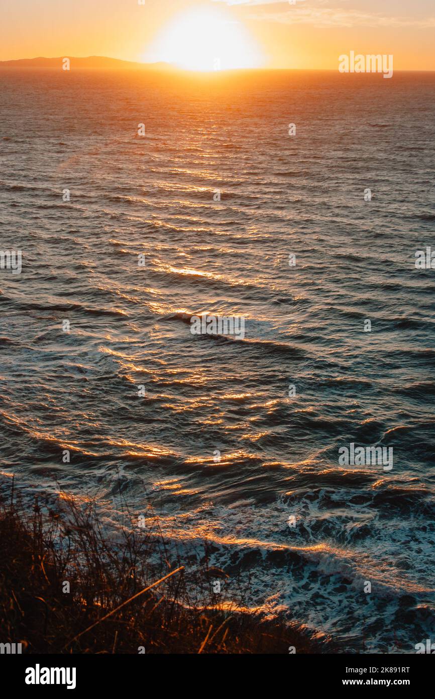 Beautiful sunset of wavy water on the seashore in Greece with mountains ...