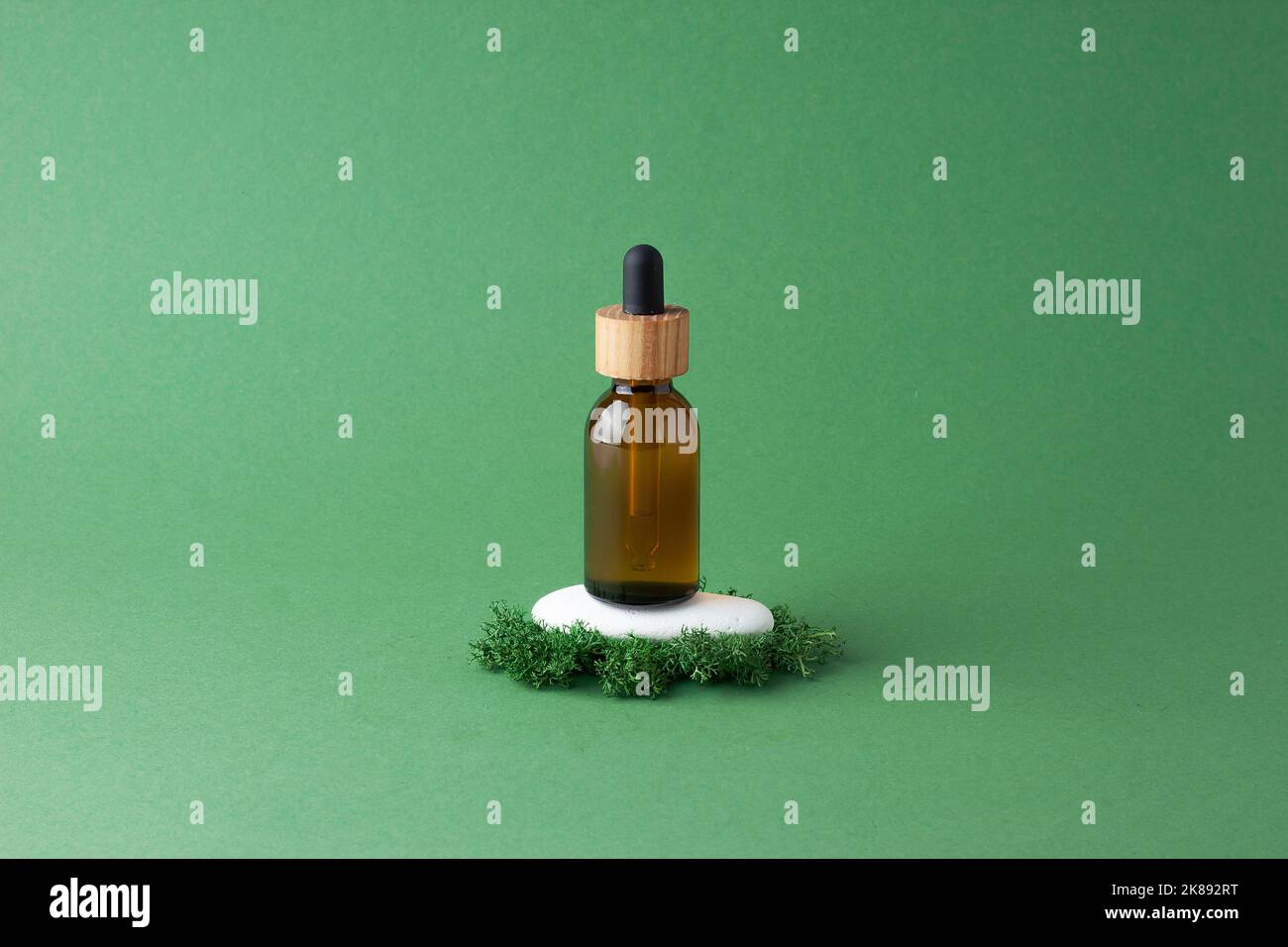 Cosmetic bottle with stone and moss on green background. Close up, copy ...