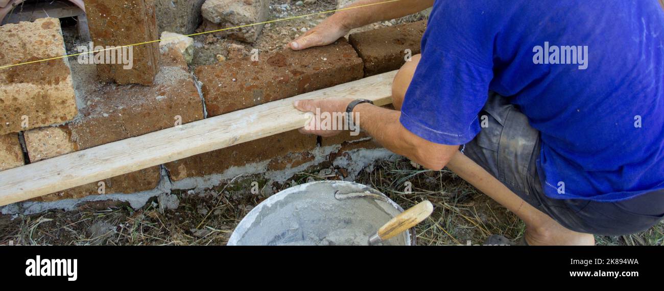 Image of an elderly bricklayer who with a board puts up some tuff ...