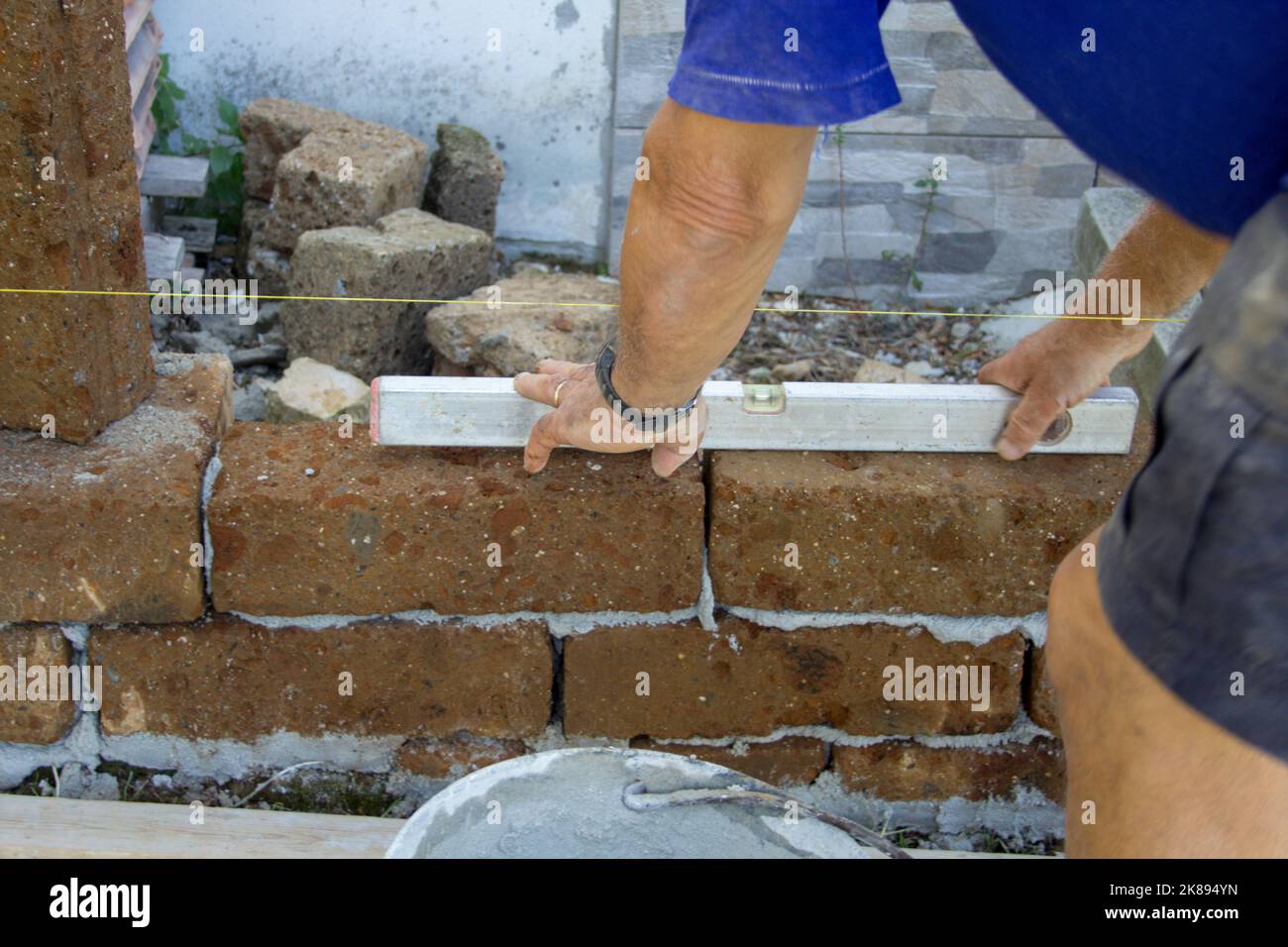 Image of the hands of a bricklayer who checks the regularity of the ...