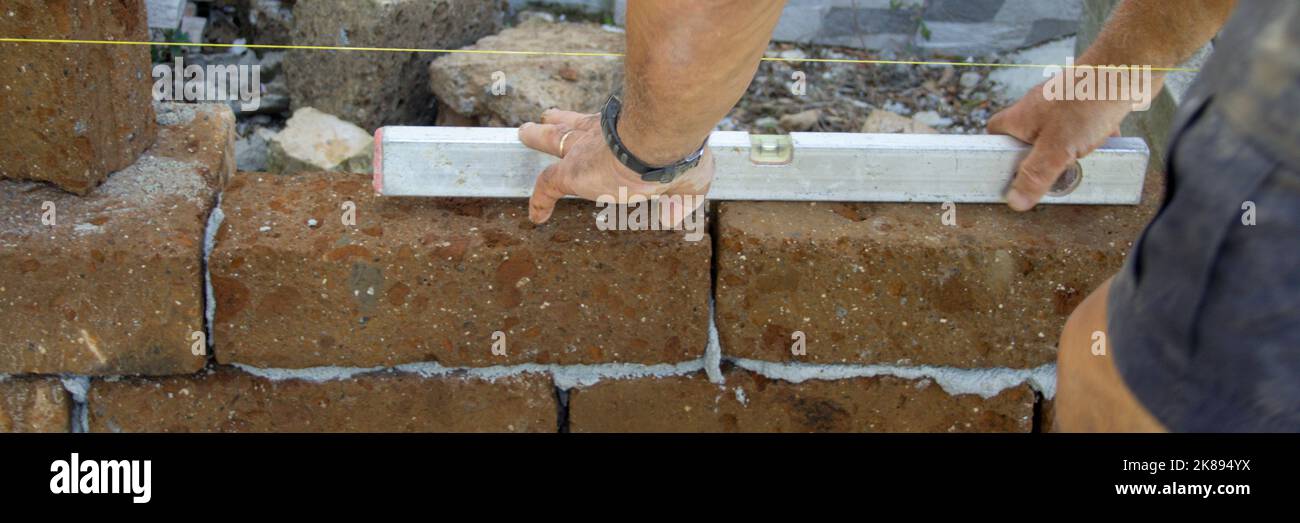 Image of the hands of a construction worker who with a level checks the ...