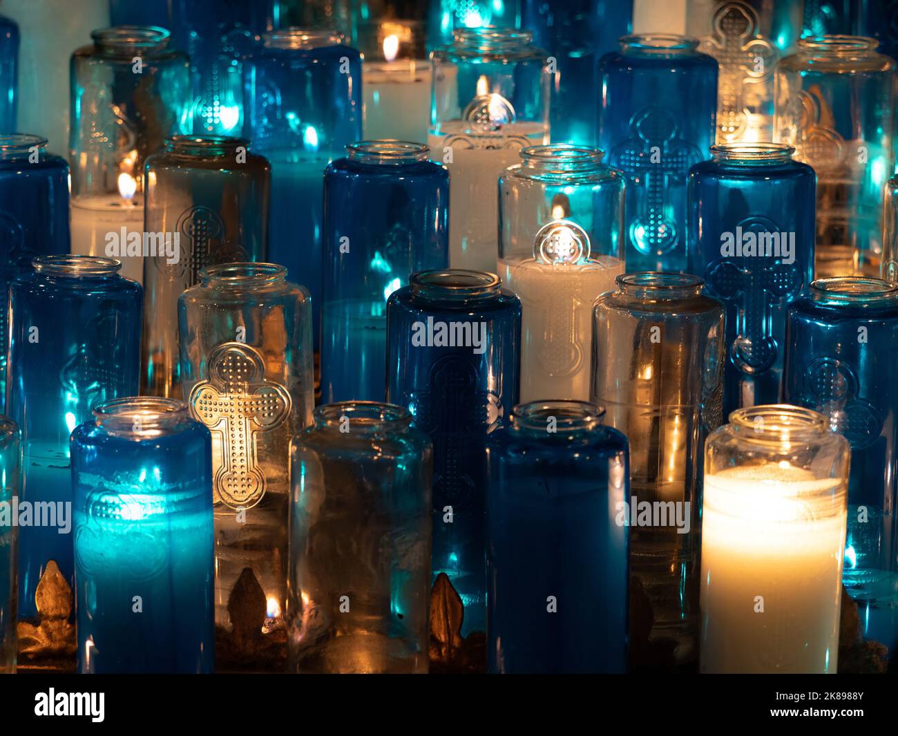 Multiple turquoise and clear glass containers holding many lit votive ...