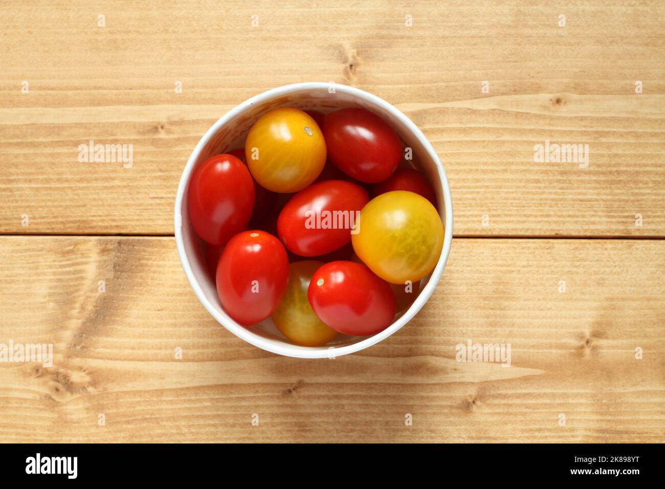 Yellow and red small tomatoes in a cardboard box on a wooden table ...