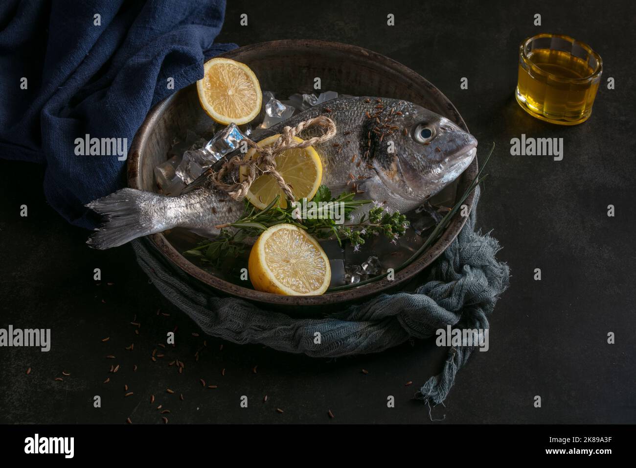 Raw fish presented in a metal dish on a dark background Stock Photo - Alamy