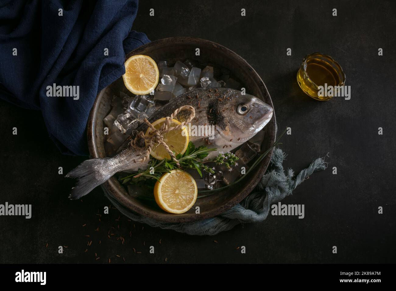 Raw fish presented in a metal dish on a dark background Stock Photo - Alamy