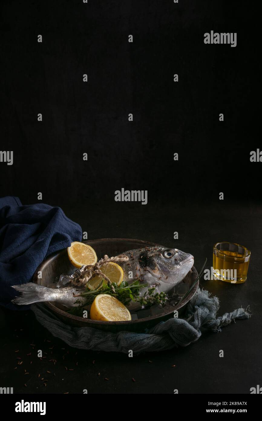 Raw fish presented in a metal dish on a dark background Stock Photo - Alamy