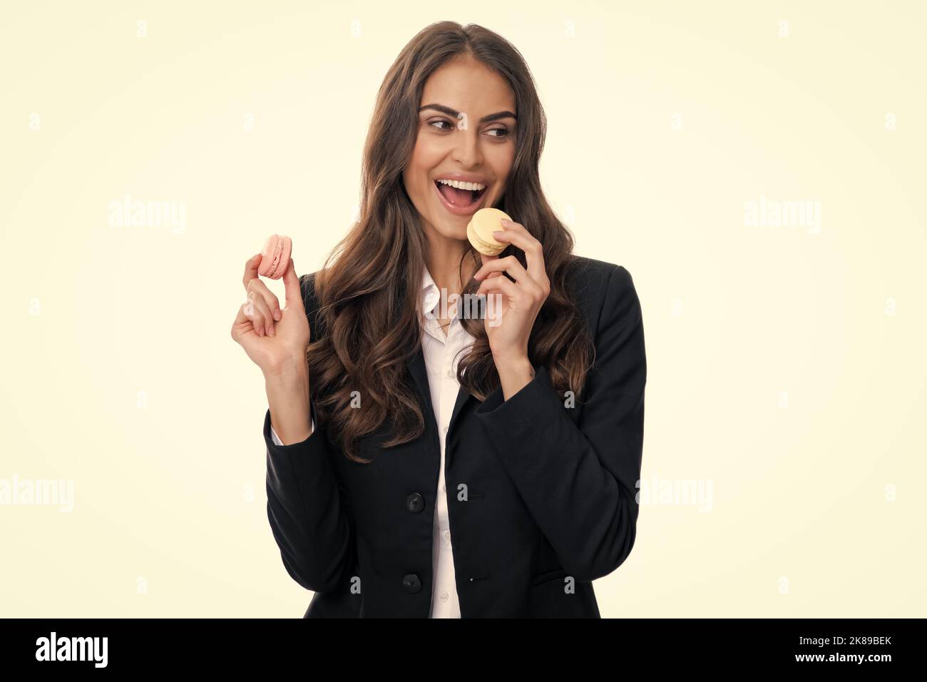Charming woman want to bite tasty macaron, holding macaroon near open ...