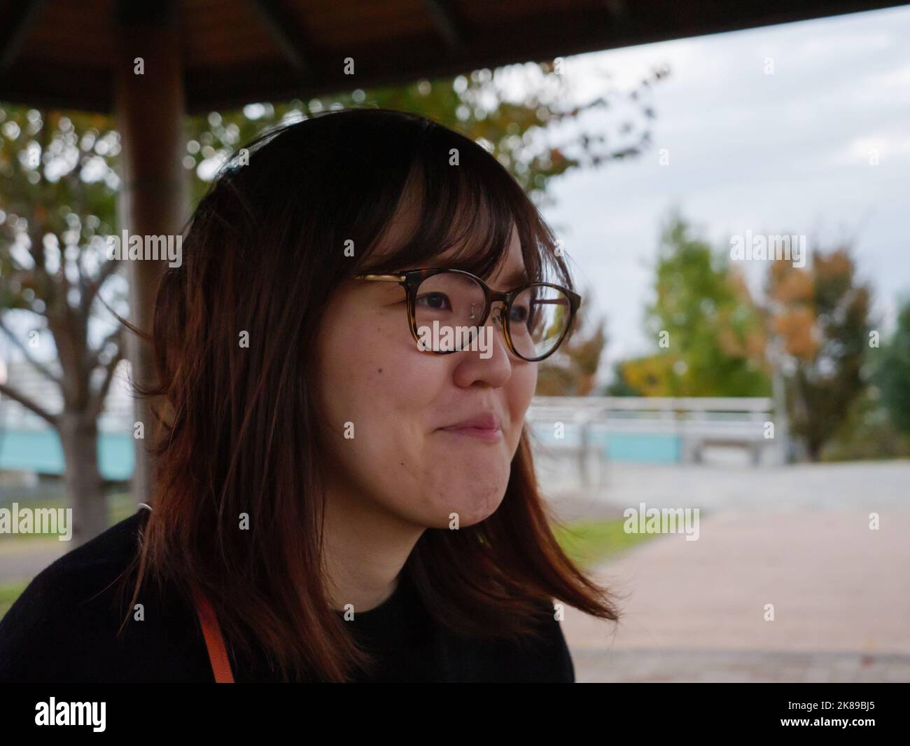 A pretty young asian woman smiling while sat outdoors Stock Photo - Alamy