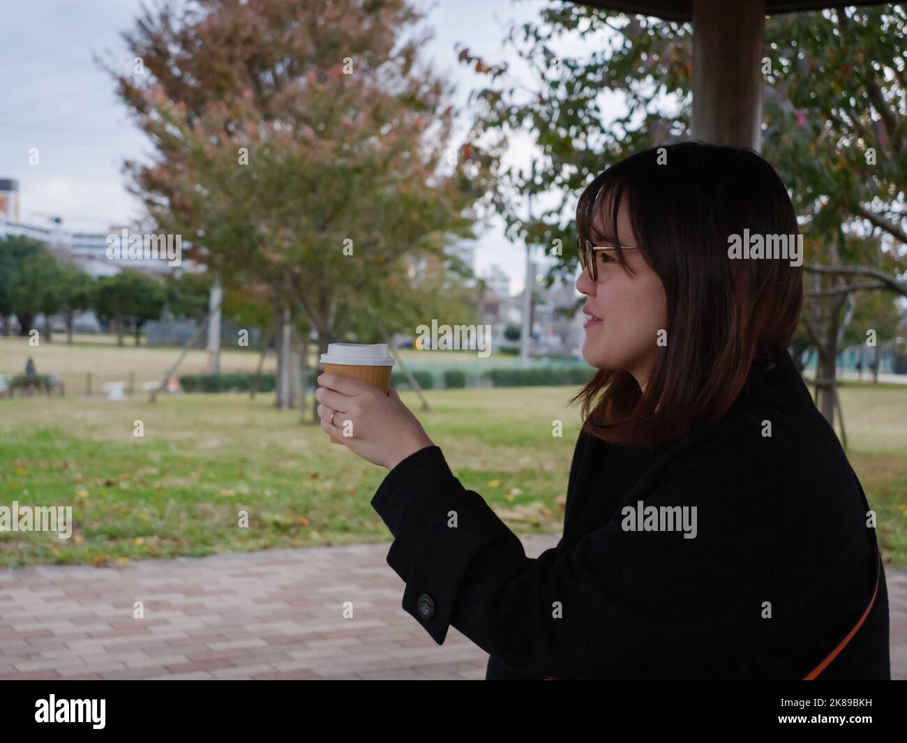 A beautiful Japanese lady drinking coffee in a park Stock Photo - Alamy