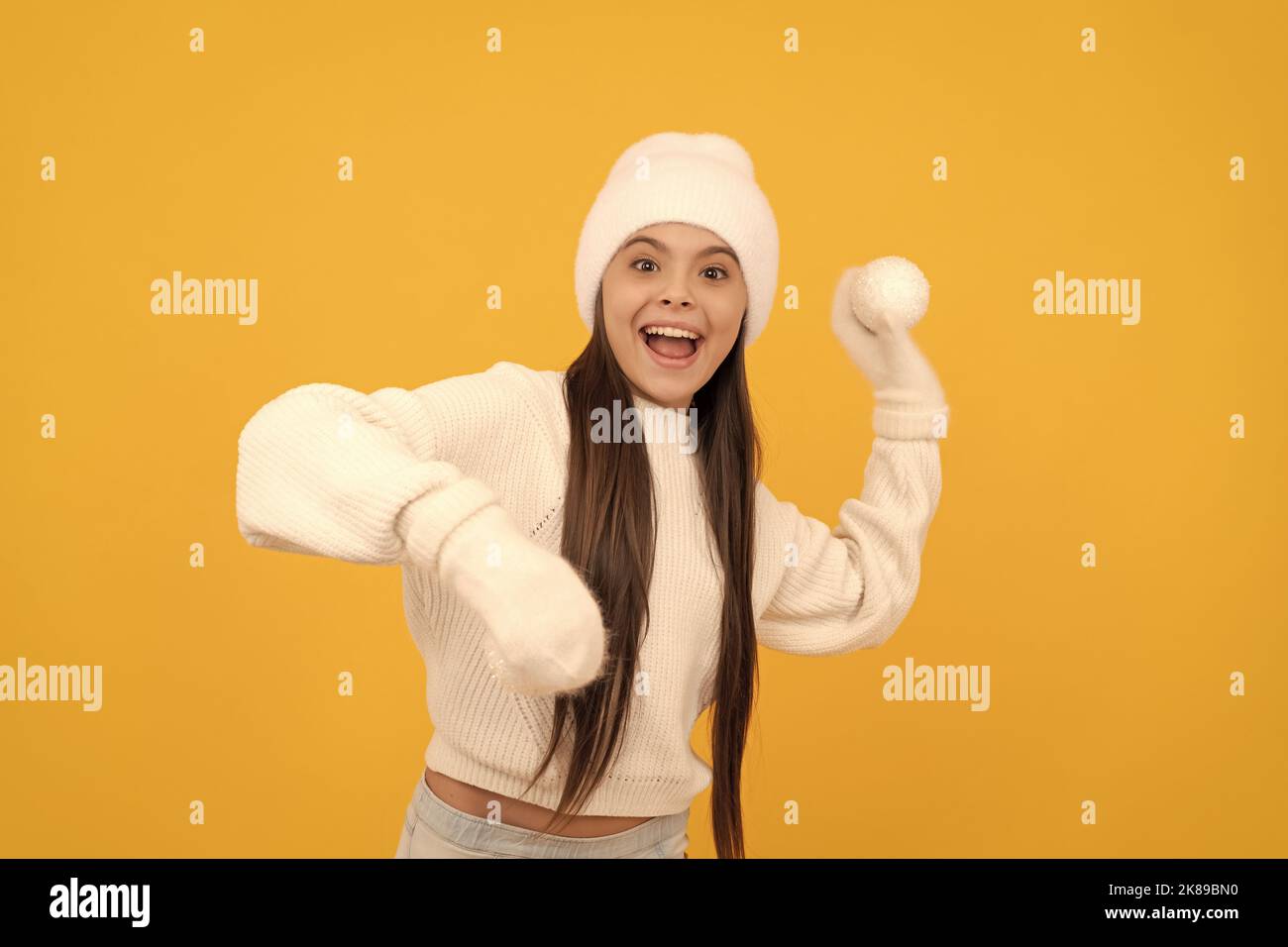 amazed kid in winter hat and gloves play with snowball on yellow ...