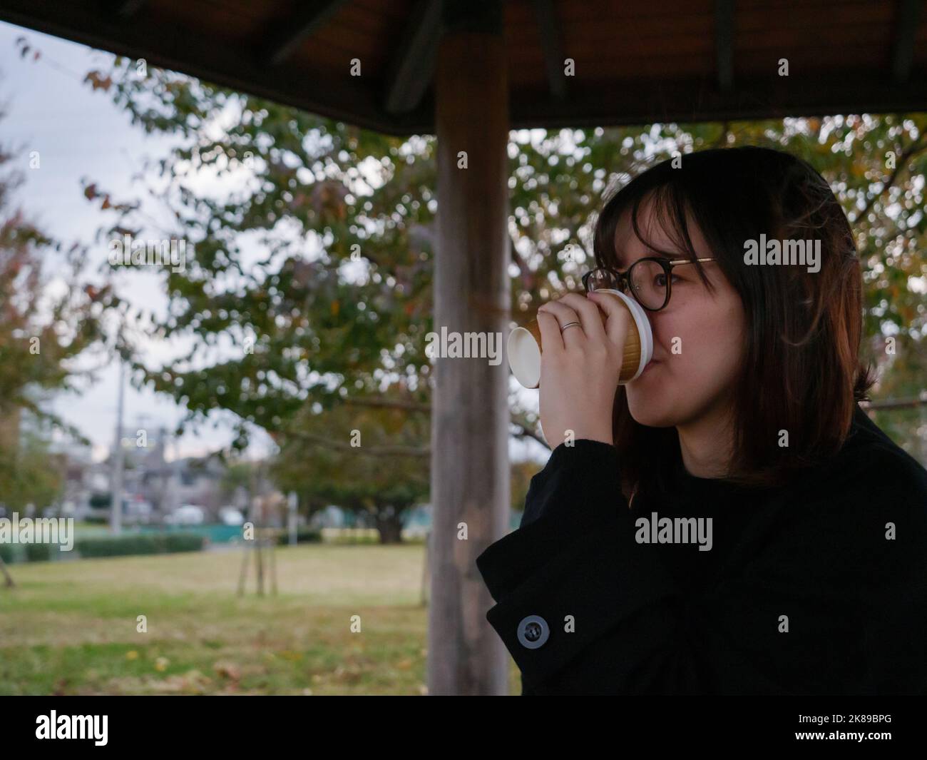 A beautiful Japanese lady drinking coffee in a park Stock Photo - Alamy