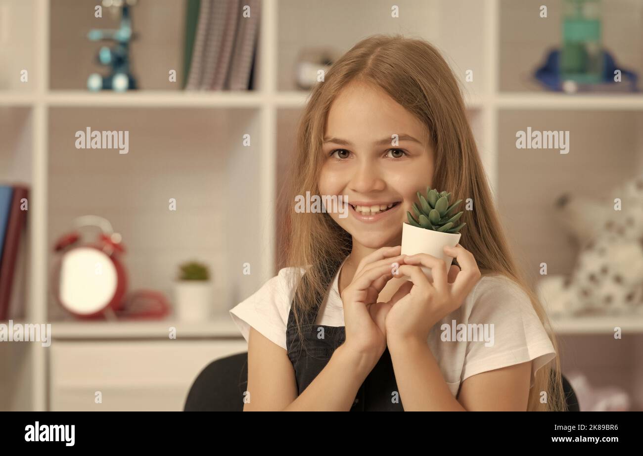 glad child hold potted plant in school classroom Stock Photo - Alamy