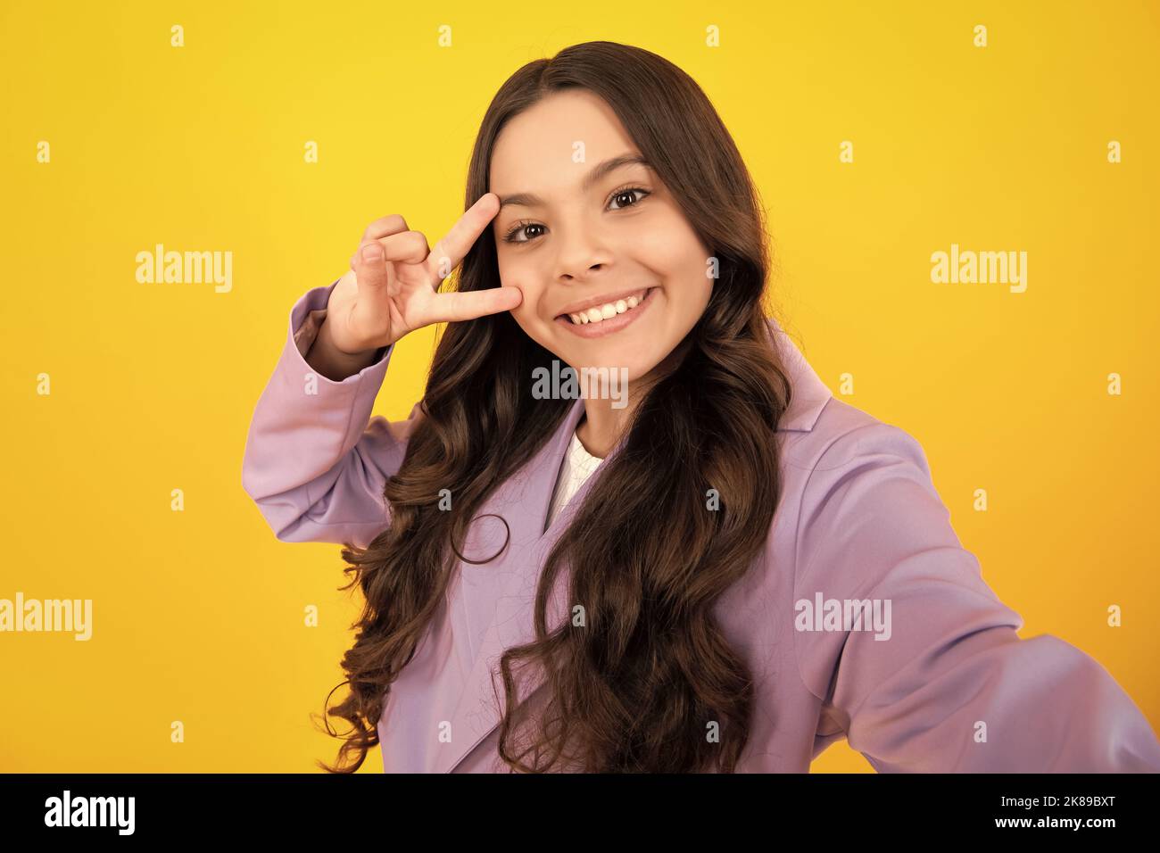 Trendy beautiful teenage model making selfie posing on yellow studio background. Teen fashion ...