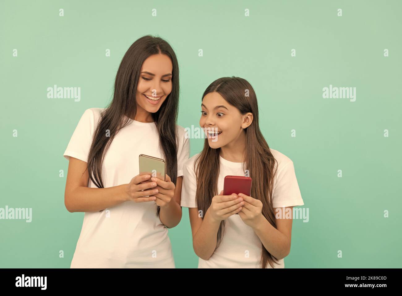 Shocked Mother And Daughter Chatting On Smartphone On Blue Background