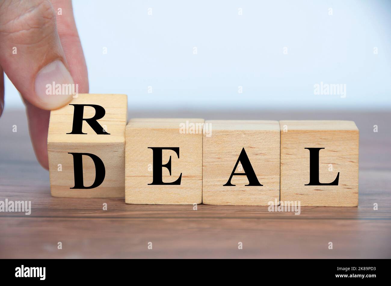 Hand turning wooden cube to form real deal text. Business concept Stock ...