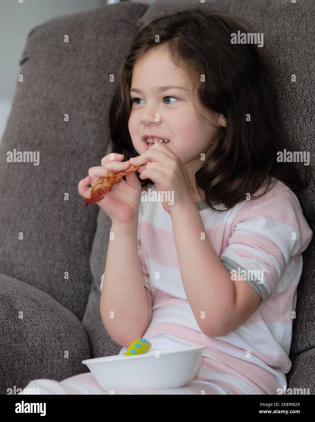 a pretty girl in a pajama is eating bacon for breakfast Stock Photo - Alamy