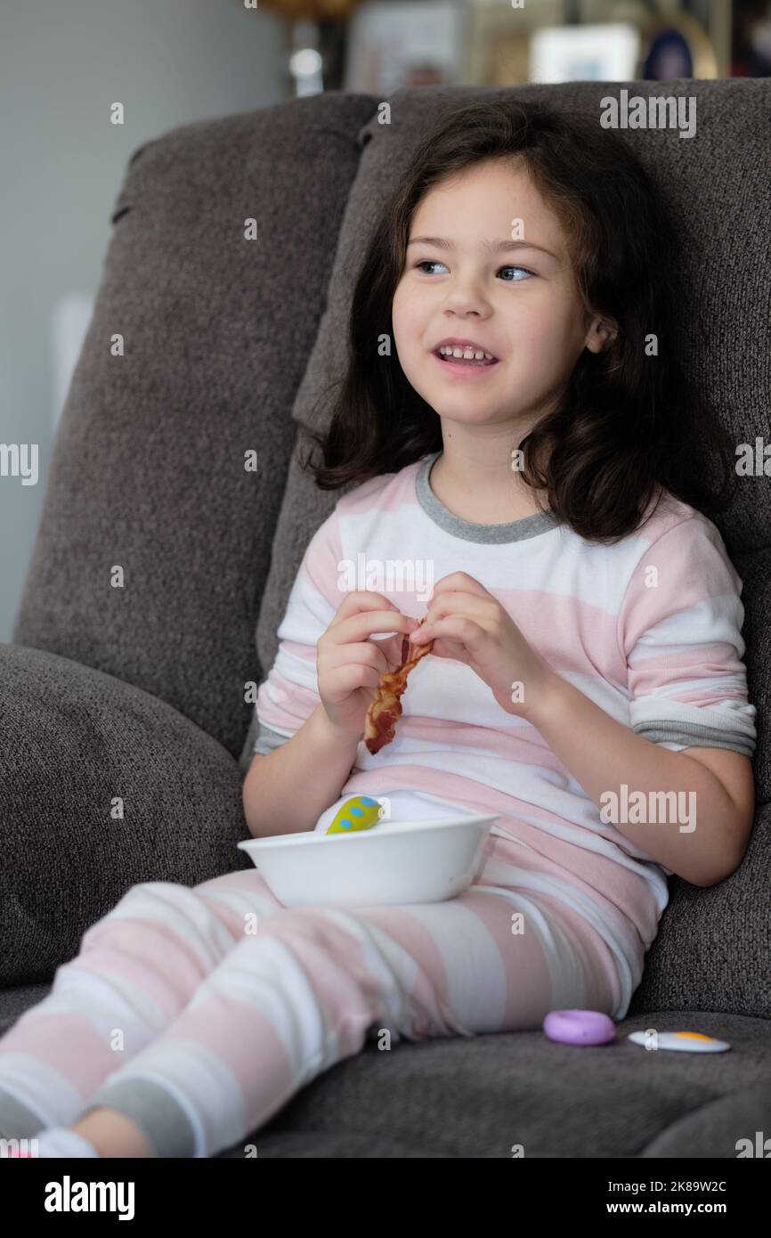 a pretty girl in a pajama is eating bacon for breakfast Stock Photo - Alamy