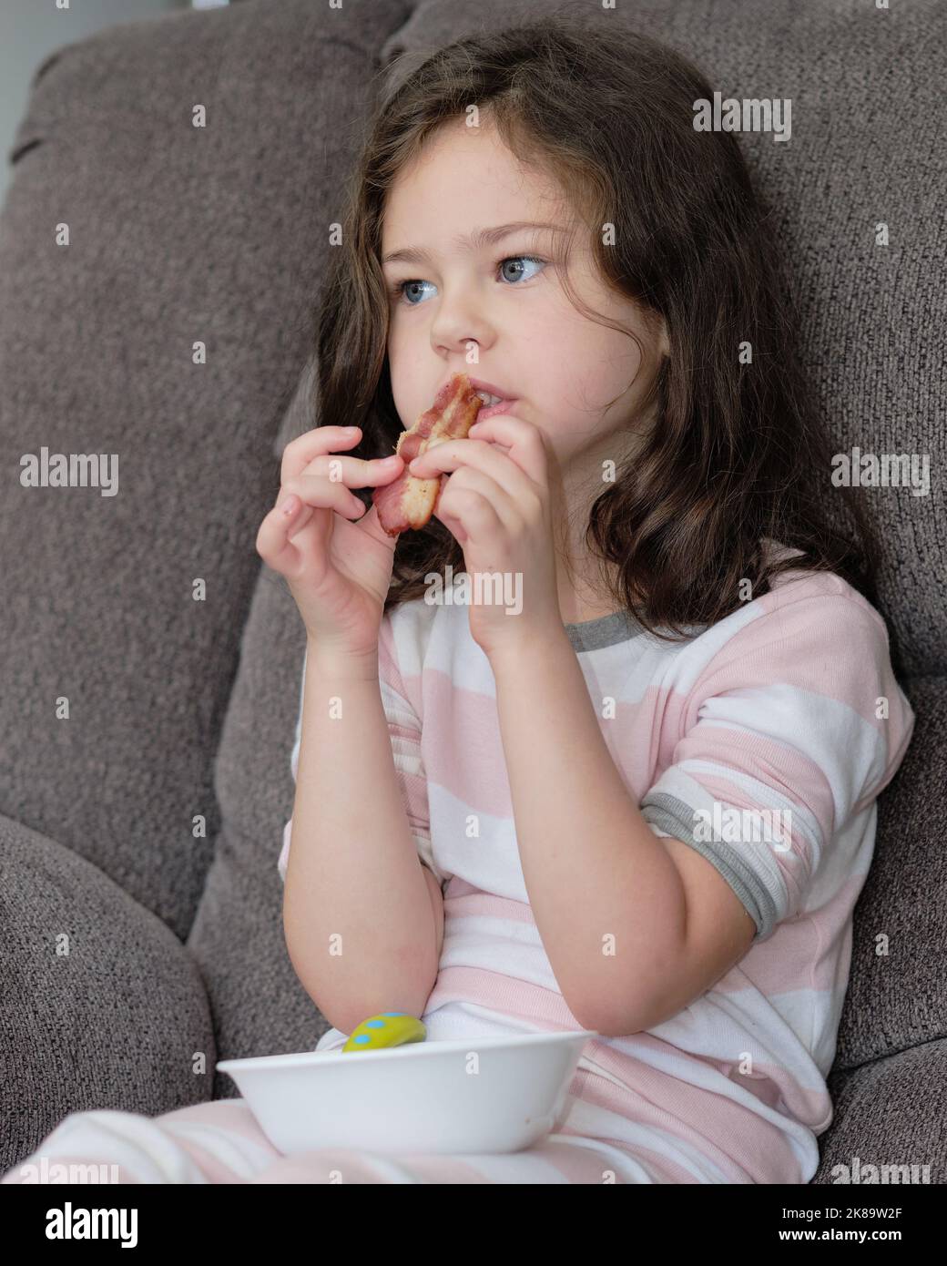 a pretty girl in a pajama is eating bacon for breakfast Stock Photo - Alamy