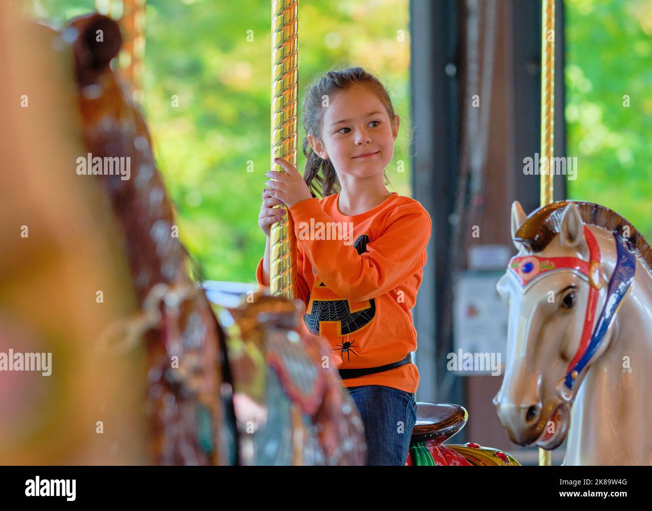 pretty girl in a halloween themed shirt is riding a carousel at the ...