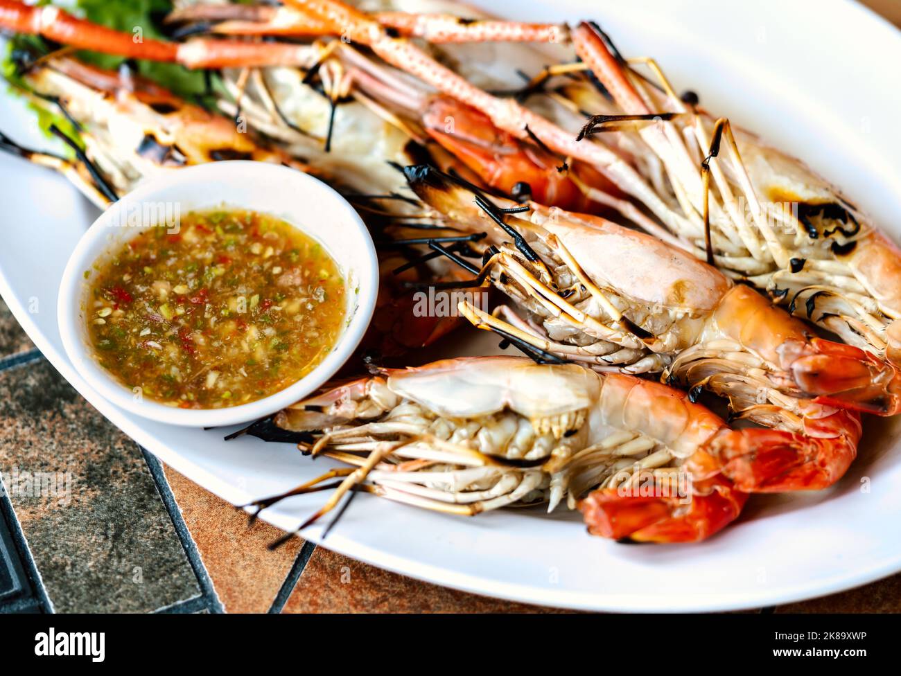 Close up grilled giant river prawns in white plate on table, close up ...