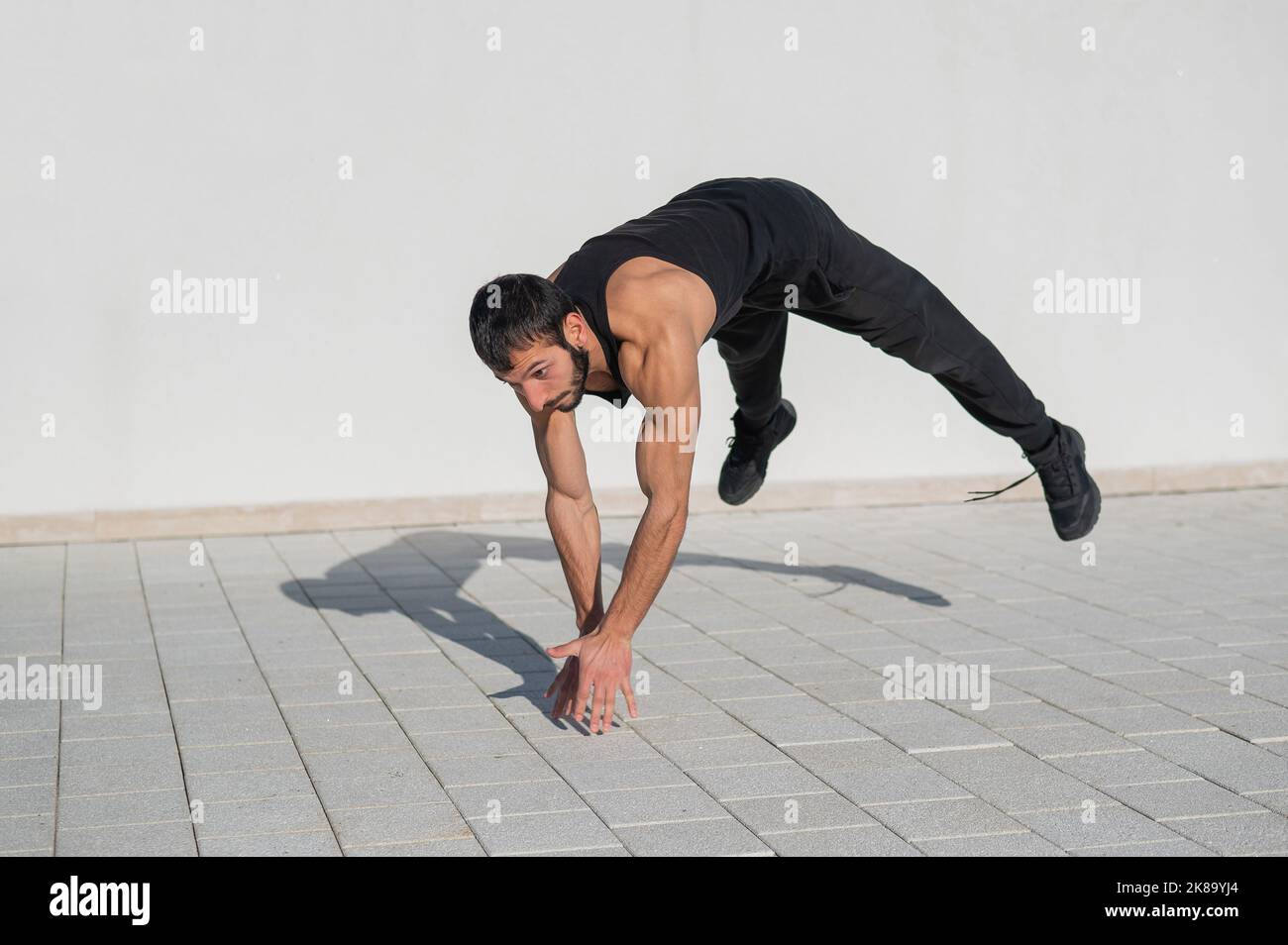 A man in black sportswear jumps while doing push-ups outdoors Stock ...