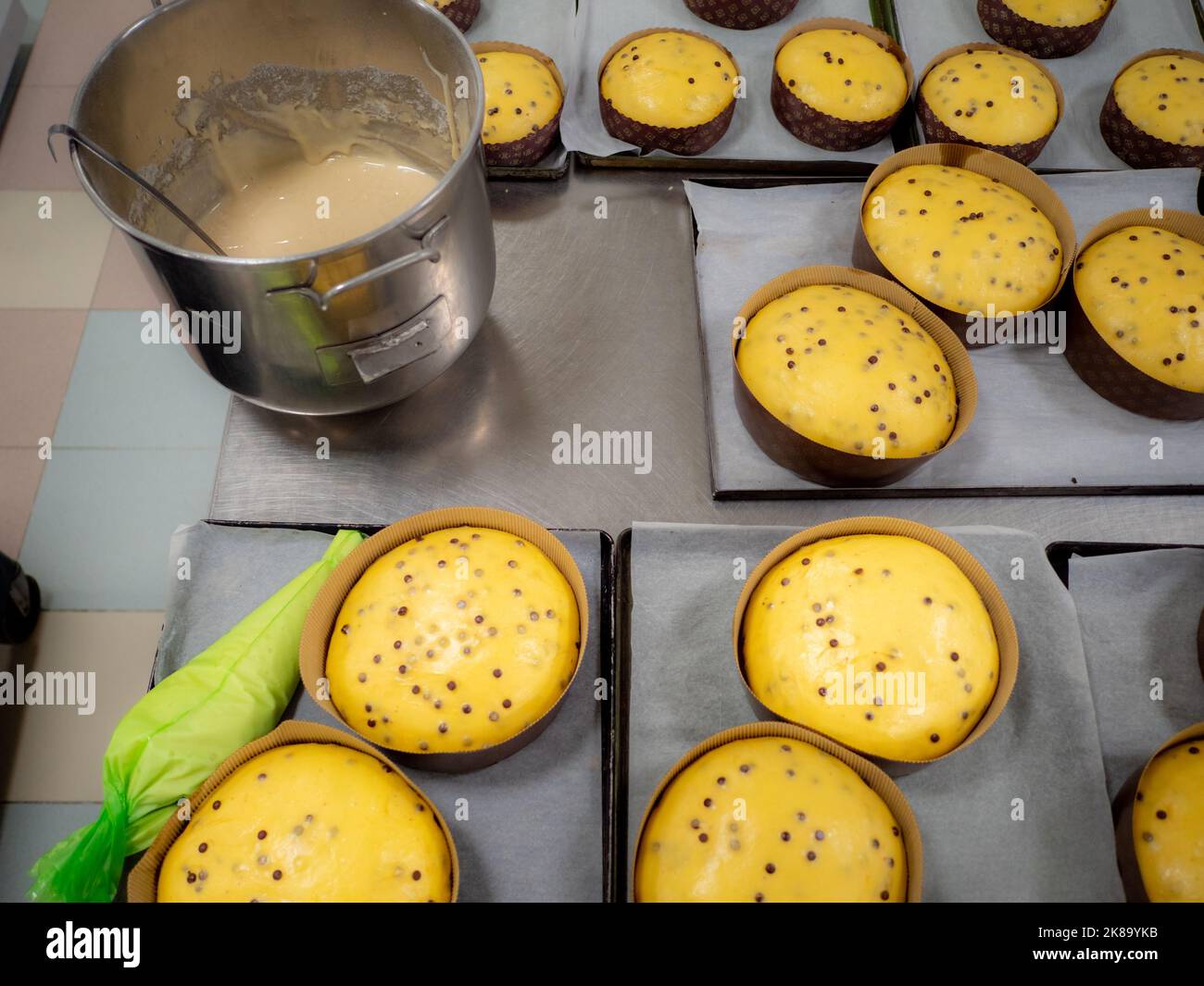artisan using frosted filling piping bag to decorate a group of cakes ...