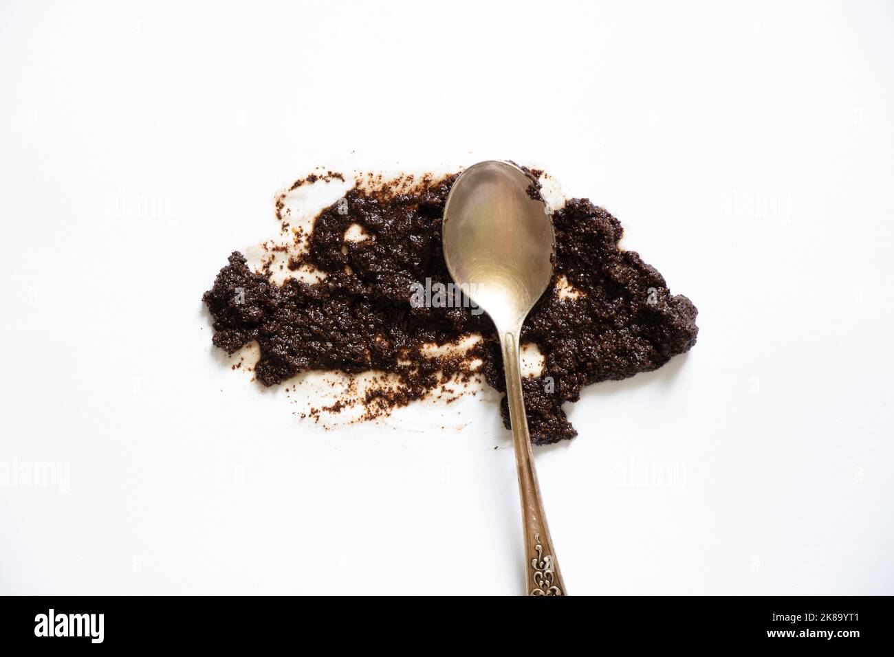 spilled coffee grounds on a white background and a teaspoon lies next ...