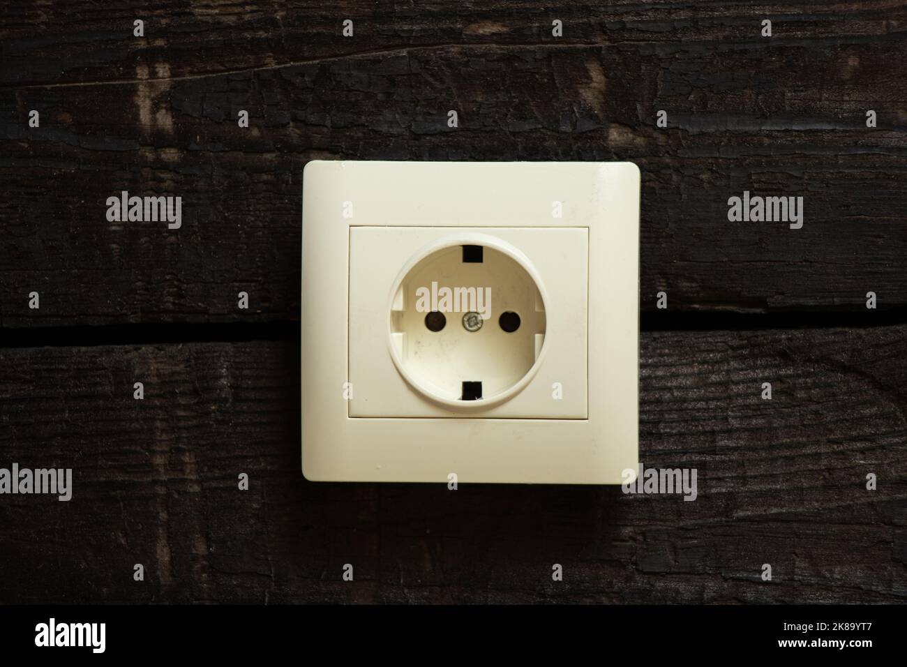 one white socket on an old burnt wood plank on the wall of a house ...
