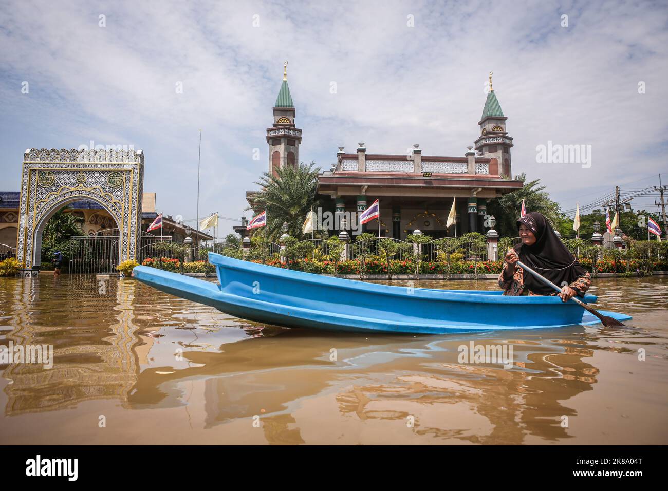 A woman rows a boat to attend prayers at the mosque due to flooding ...