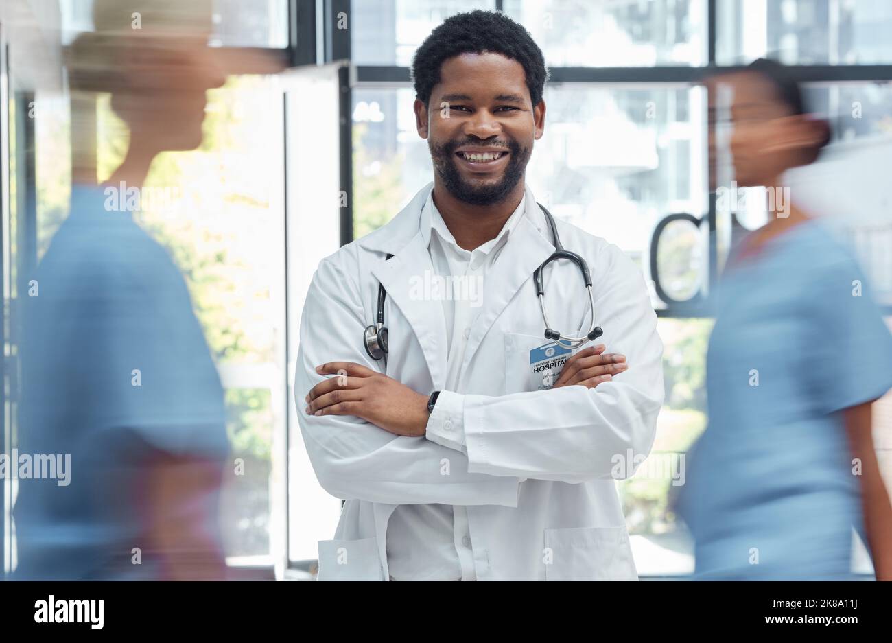Medical doctor, man nurse and crossed arms healthcare professional in busy hospital. Portrait ...