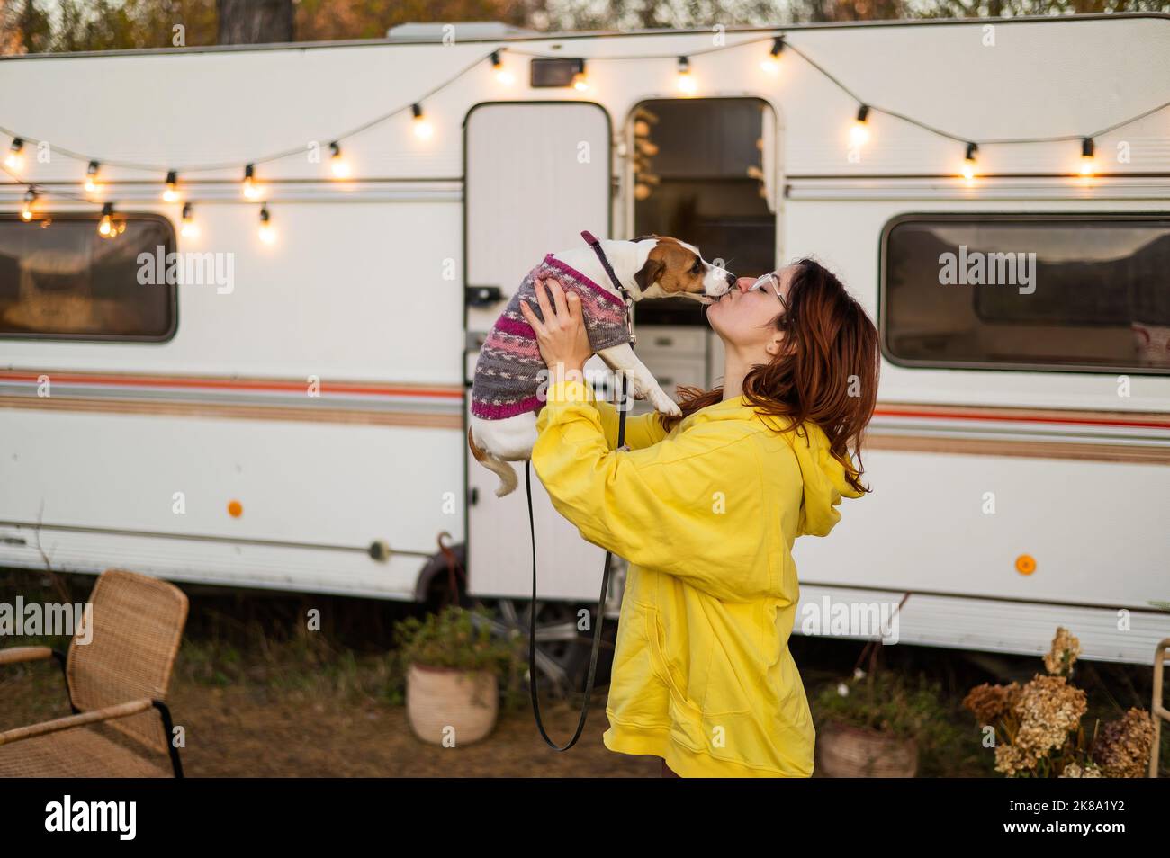 Red-haired Caucasian woman hugs a dog and lives in a motor home. Travel ...